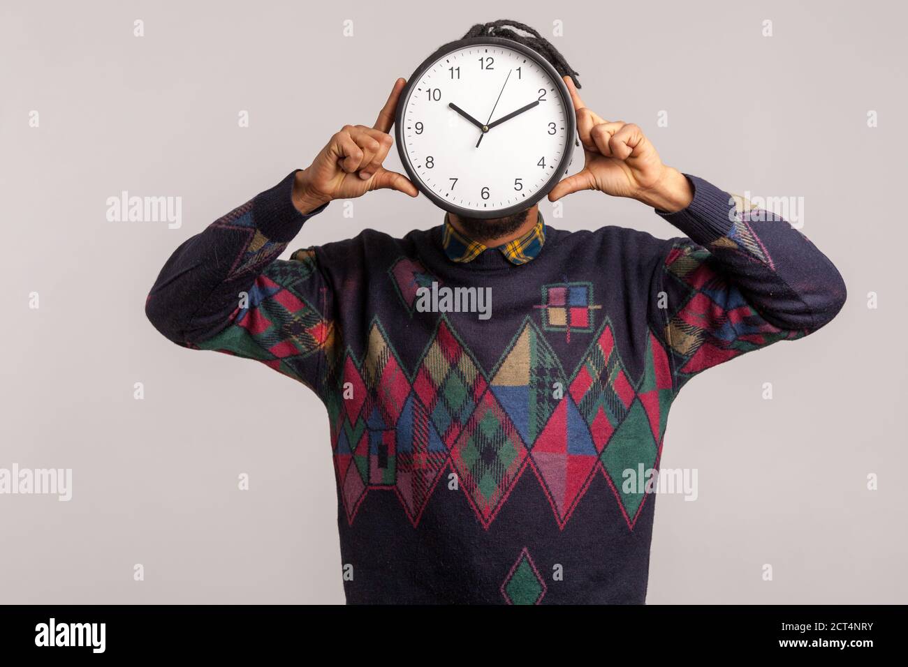 Time to work! African man hiding face behind big wall clock, afraid of ...
