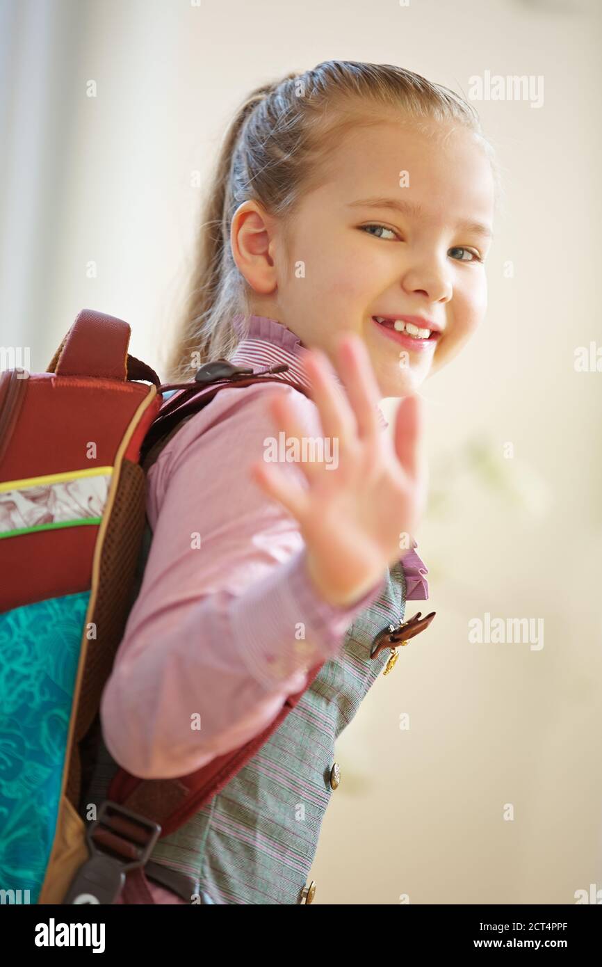 Smiling girl with satchel goes to school and waves goodbye Stock Photo ...