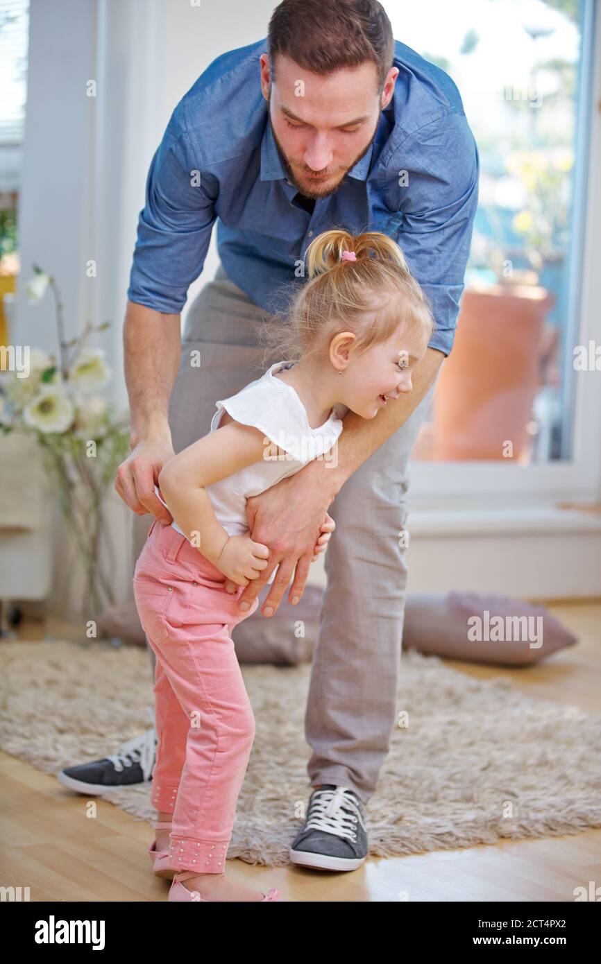 Father helps his daughter put on pants at home Stock Photo - Alamy