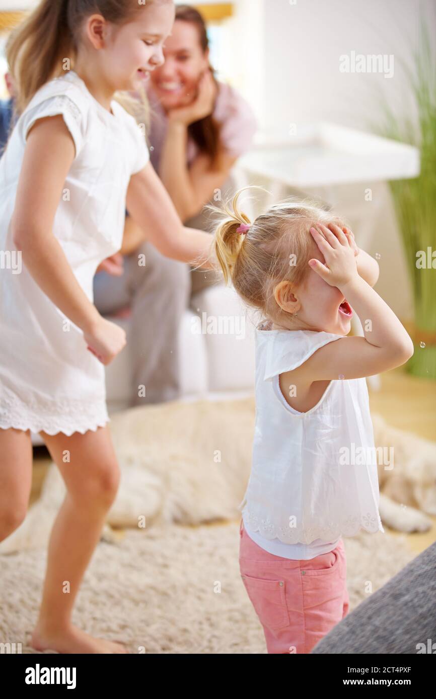 Two children play together at home and the parents watch Stock Photo ...