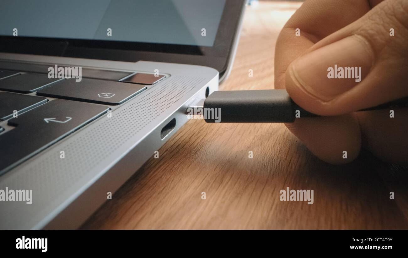 Close-up Macro Shot: Laptop on the Desk, Person Inserts USB-C Cable ...