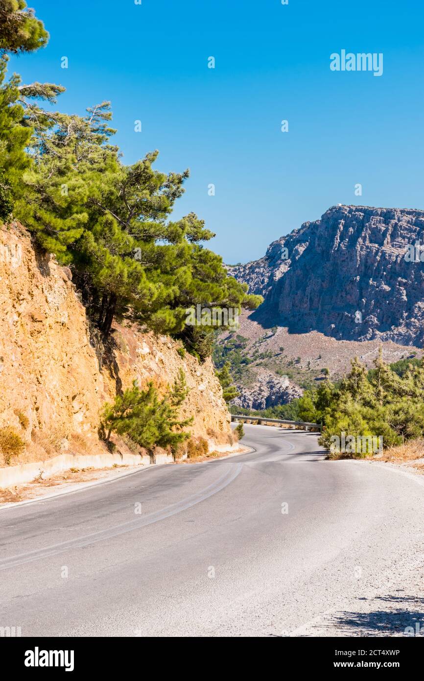 Asphalt road in the mountains of Karpathos island, with a white chapel ...