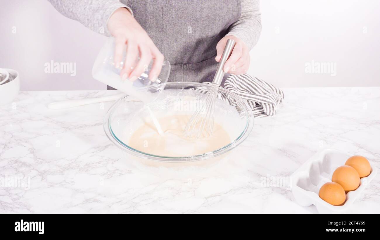 Mixing ingredient in a glass mixing bowl to make the crepes batter ...