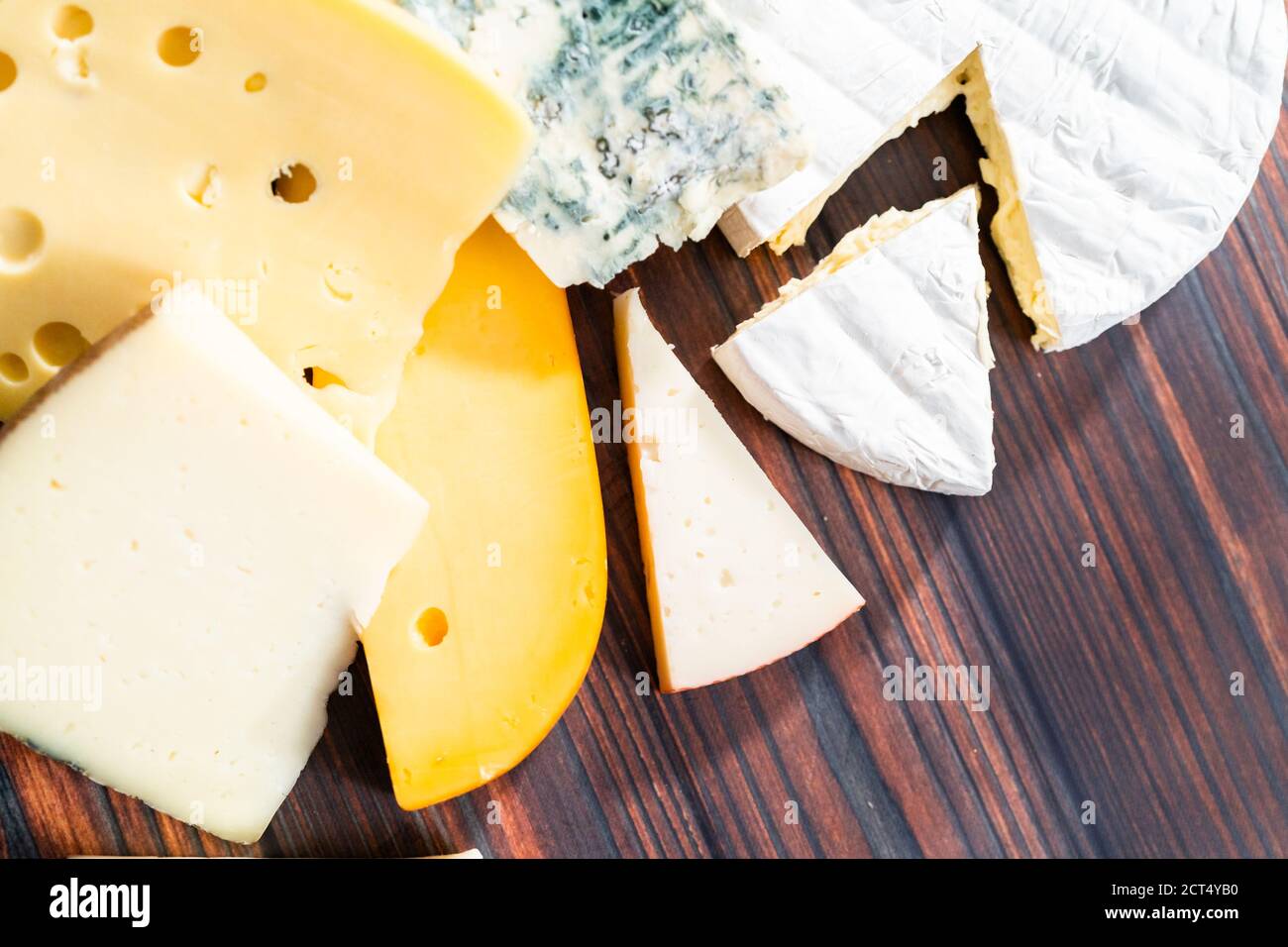Variety of large gourmet cheese wedges on a dark wooden background ...