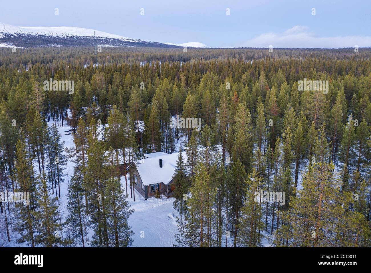 Aerial of wooden cabin in the remote forest, with snow covered woods ...