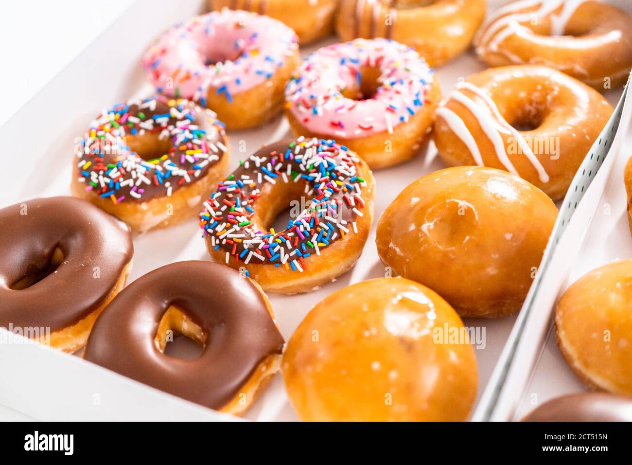 Variety of store-bought doughnuts in a white paper box Stock Photo - Alamy