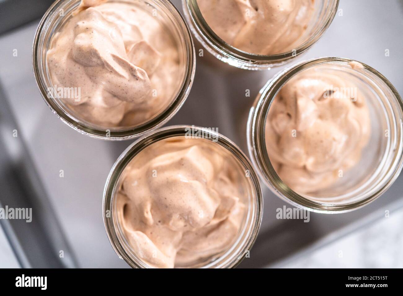 Scooping mixture into the small glass jars to make homemade chocolate ...