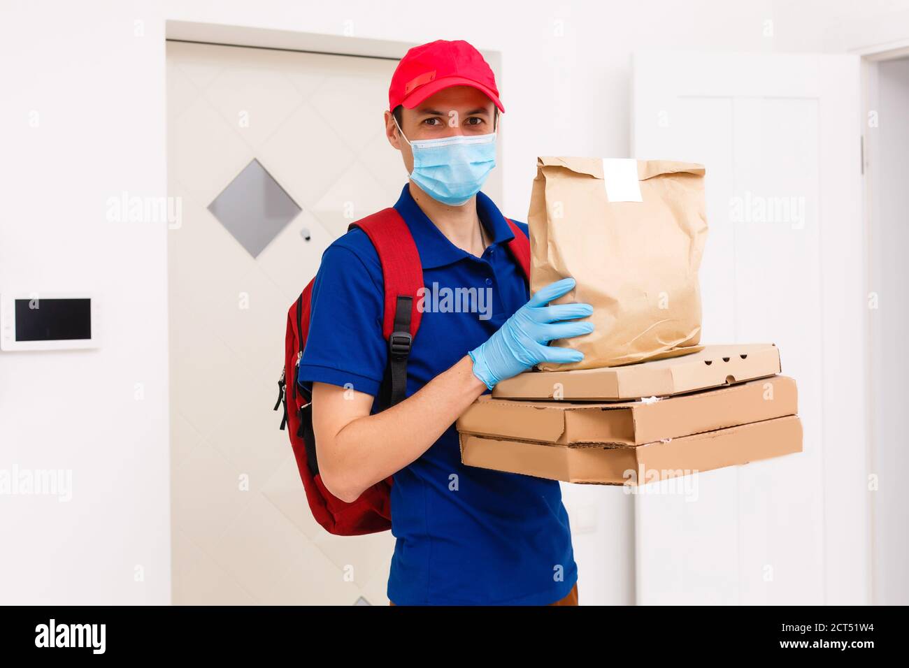 Delivery man employee in red cap t-shirt uniform mask gloves give food ...