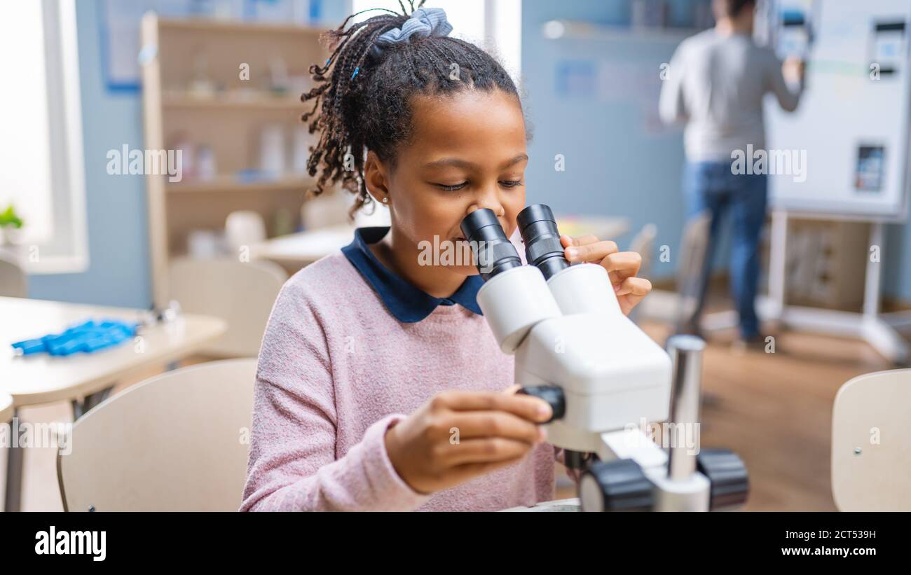 Portrait of Smart Little Schoolgirl Looking Under the Microscope. In ...