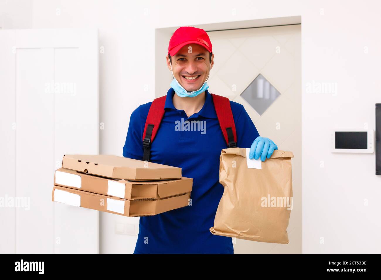 Delivery man employee in red cap t-shirt uniform mask gloves give food ...