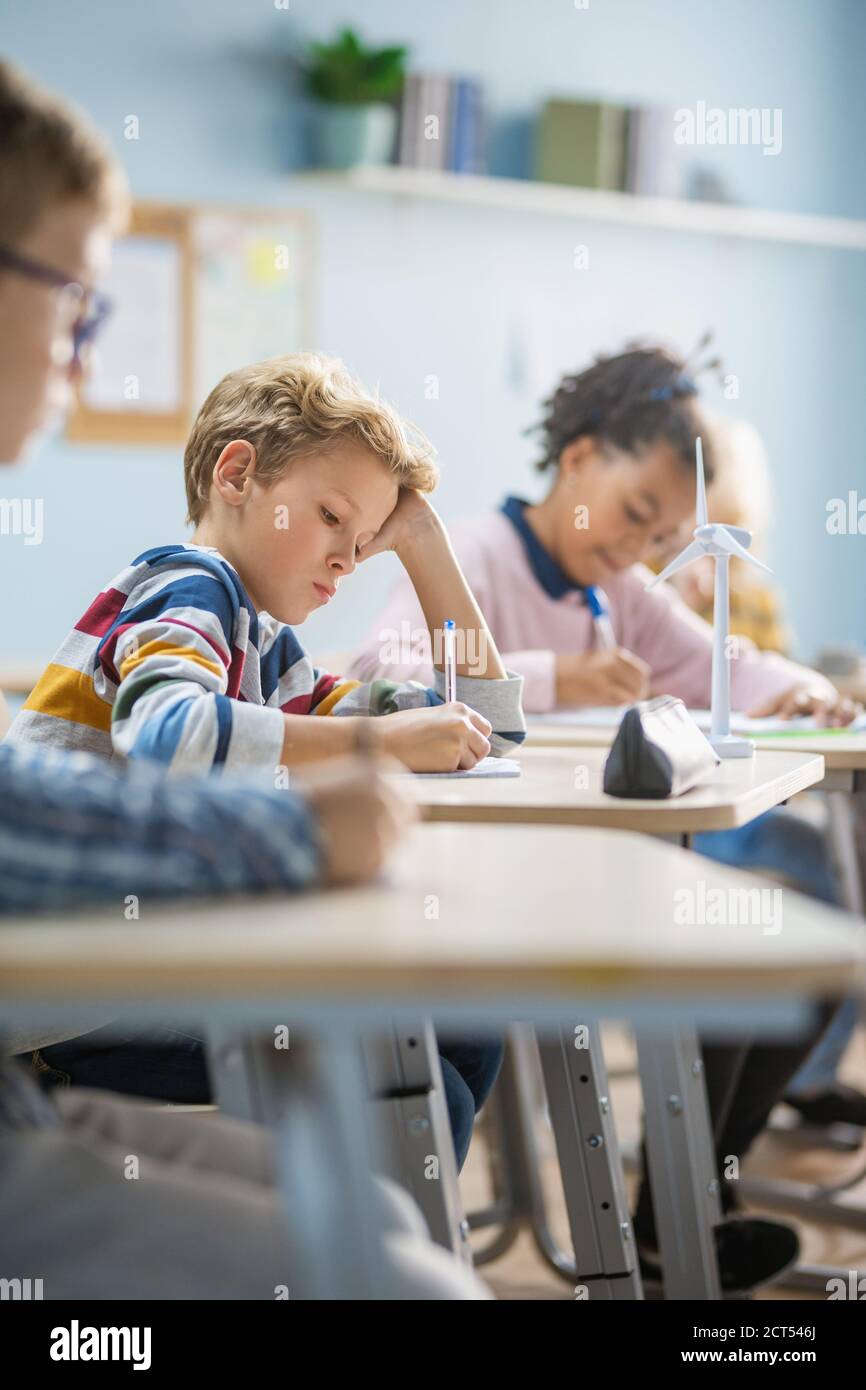 In Elementary School Classroom Brilliant Caucasian Boy Writes in ...
