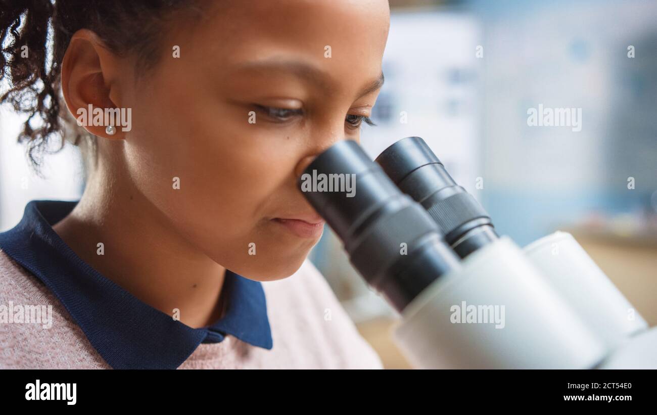 Portrait of Smart Little Schoolgirl Looking Under the Microscope. In ...