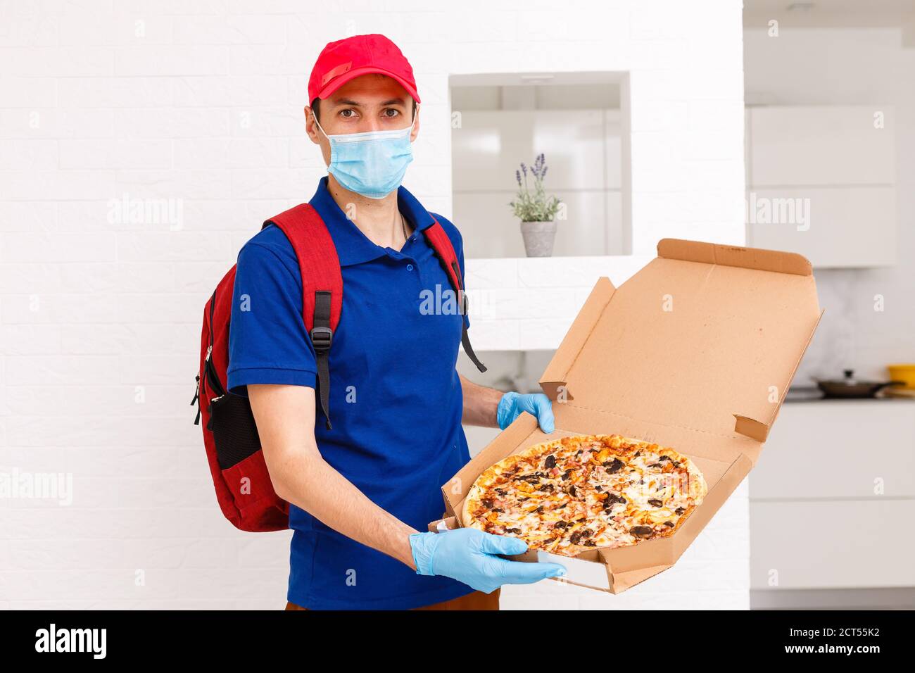 Delivery man employee in red cap t-shirt uniform mask gloves give food ...