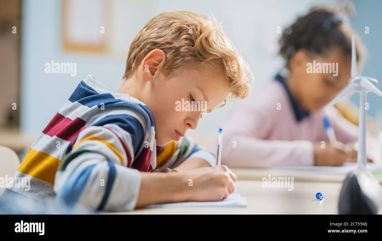 In Elementary School Classroom Brilliant Caucasian Boy Writes in ...