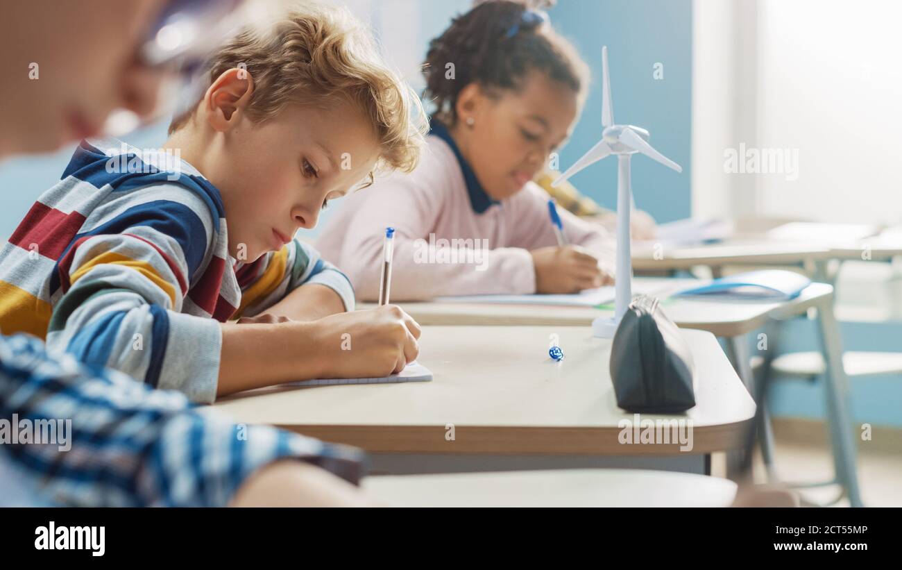 In Elementary School Classroom Brilliant Caucasian Boy Writes in ...