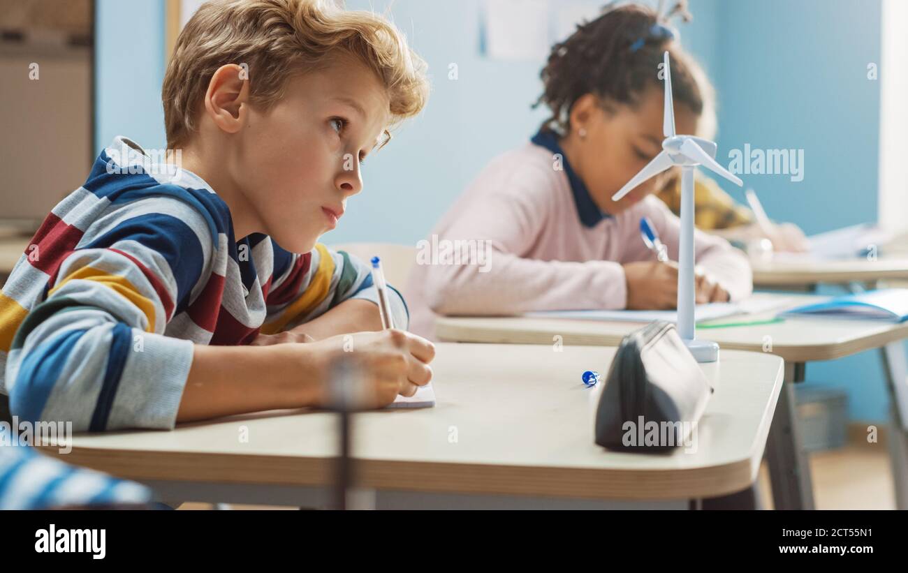 In Elementary School Classroom Brilliant Caucasian Boy Writes in ...