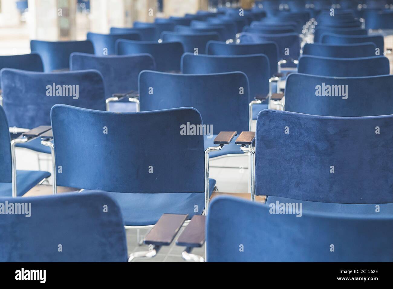 Back view of the rows of blue chairs in a conference hall; no people ...