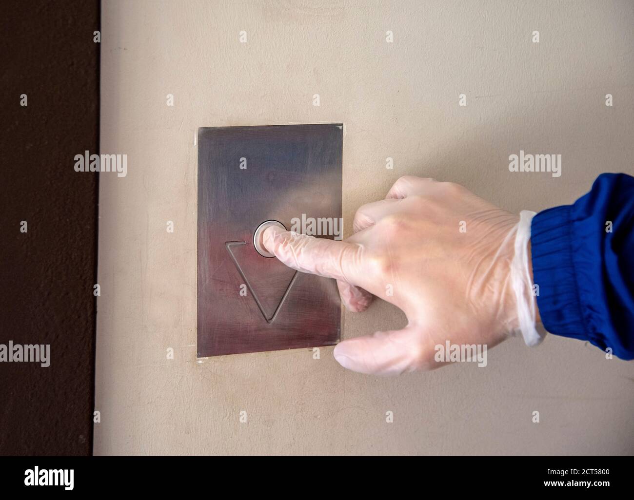 A man's hand in a rubber glove, pressing the button to call the ...