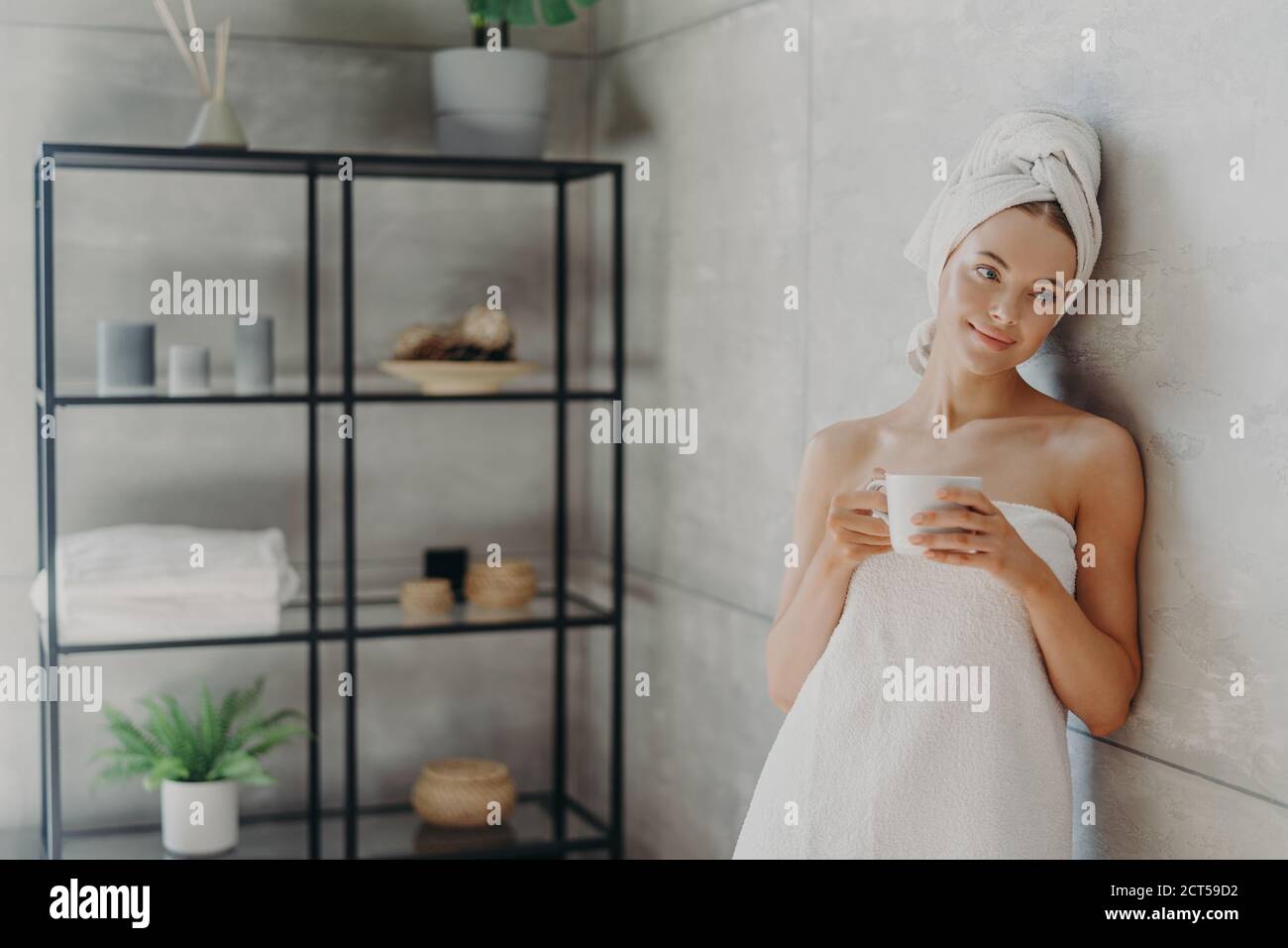 Photo of calm relaxed woman poses in towel against bathroom interior ...