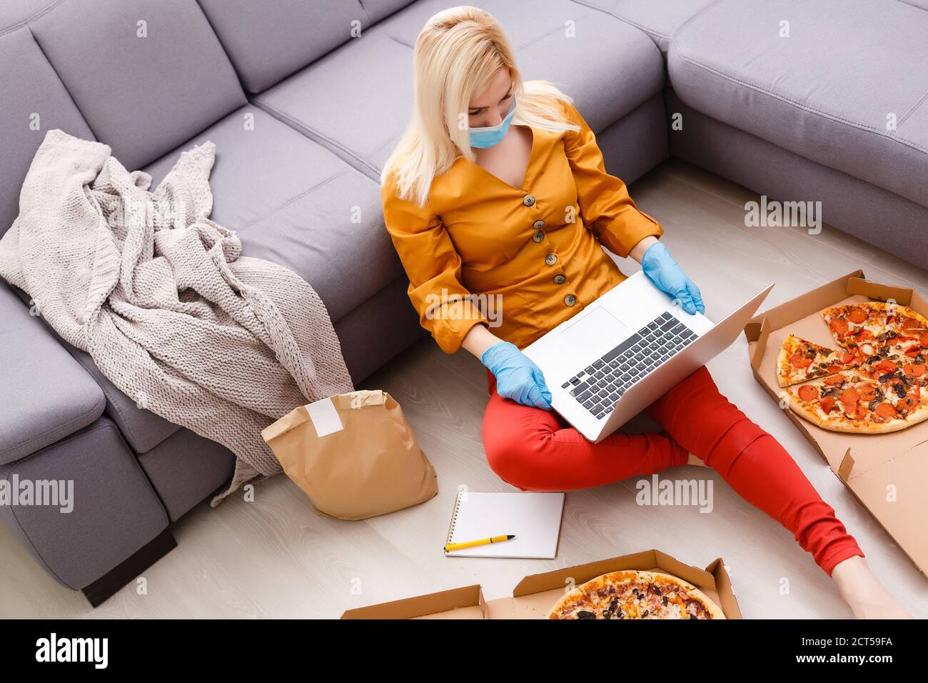 woman in protective gloves and mask with pizza at home during ...
