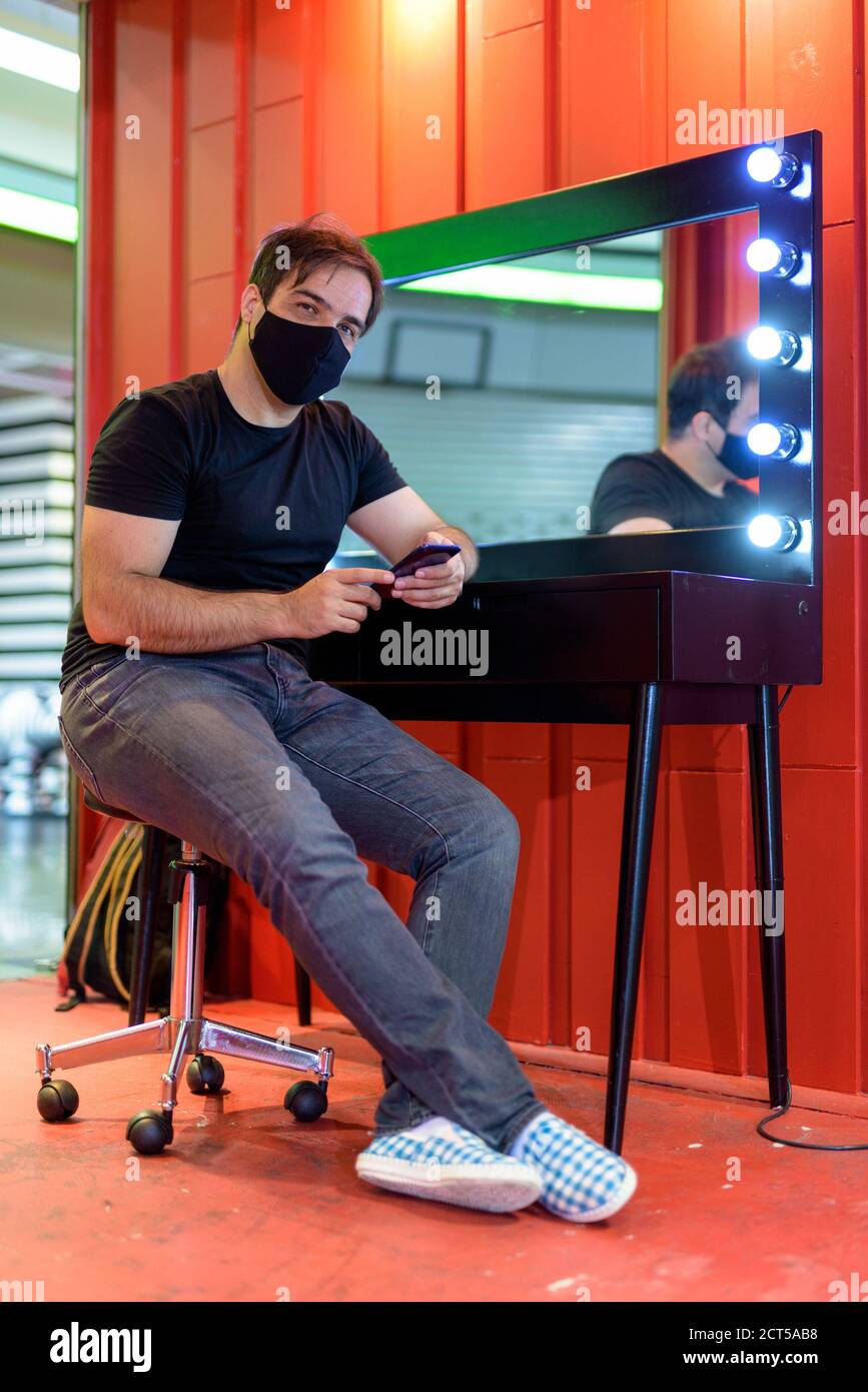 Full body shot of Persian man with mask against mirror in the makeup ...