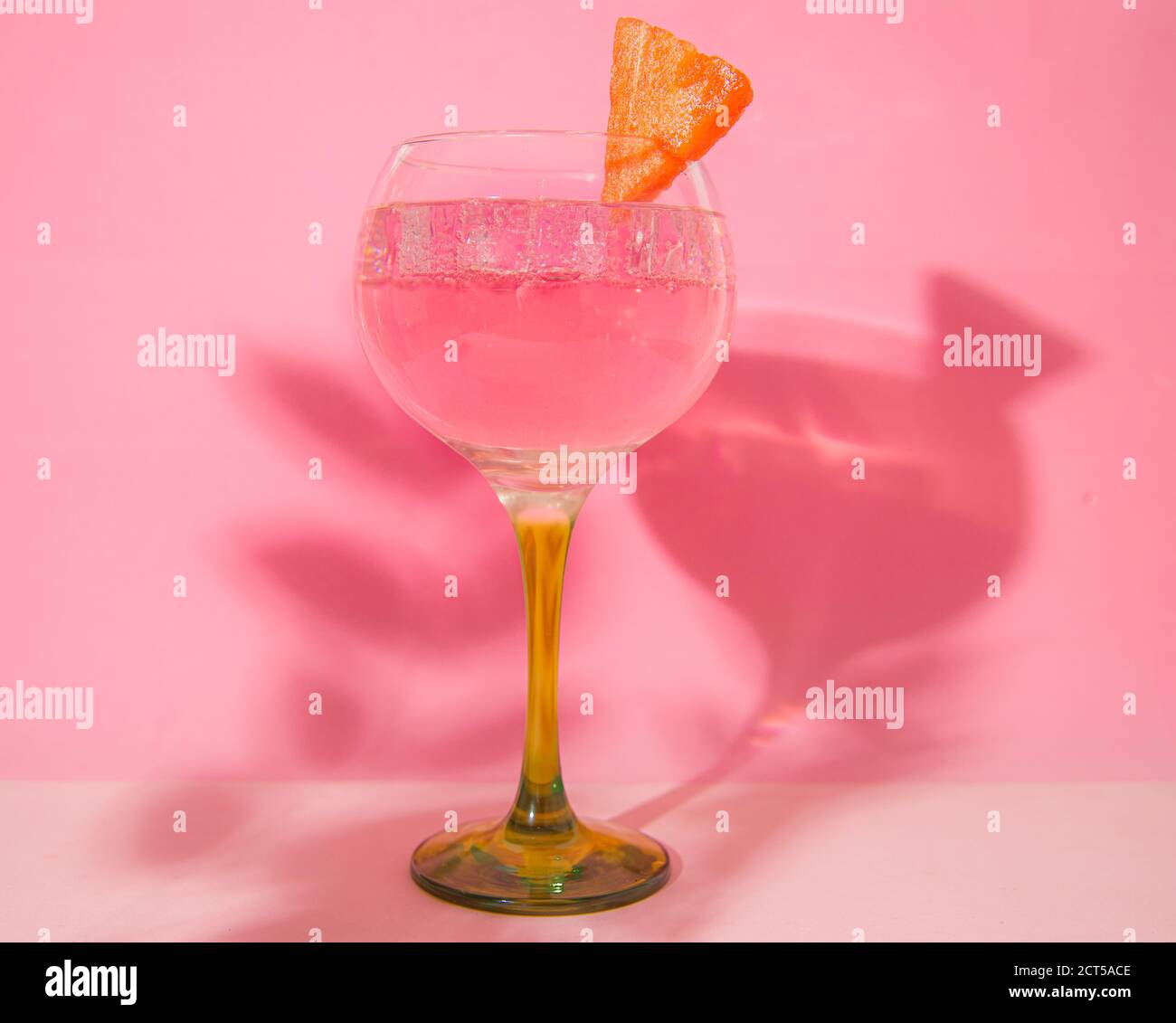 Glass of gin and tonic on a pink background Stock Photo - Alamy