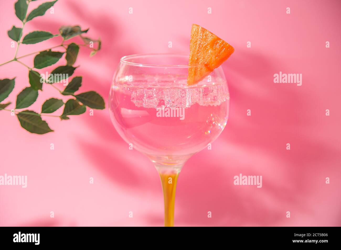 Glass of gin and tonic on a pink background Stock Photo - Alamy