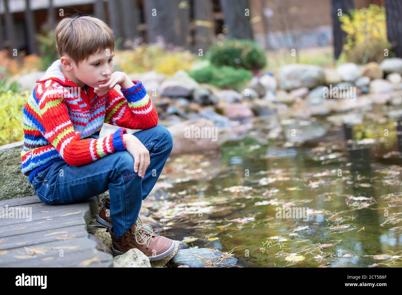 Child on an autumn walk. Sad boy by the lake Stock Photo - Alamy