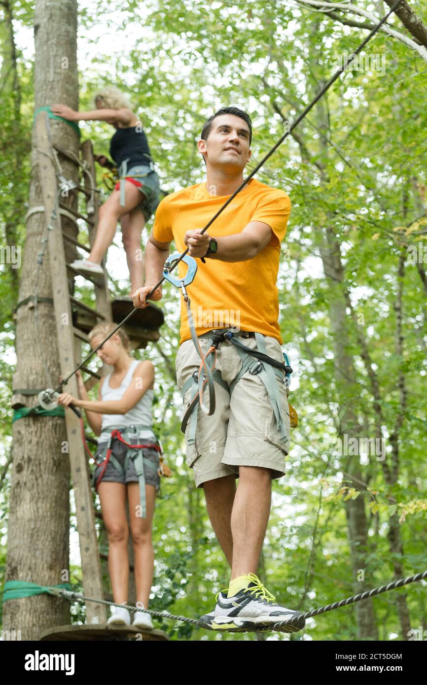 adult male walking across rope bridge between the trees Stock Photo - Alamy