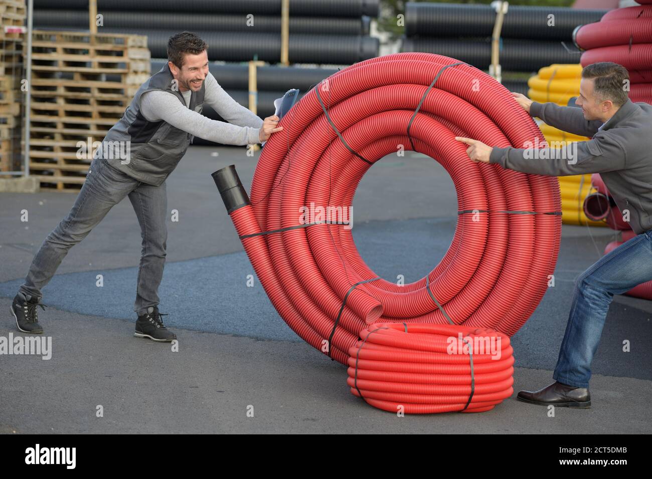 happy workers moving heavy pipes outdoors Stock Photo - Alamy