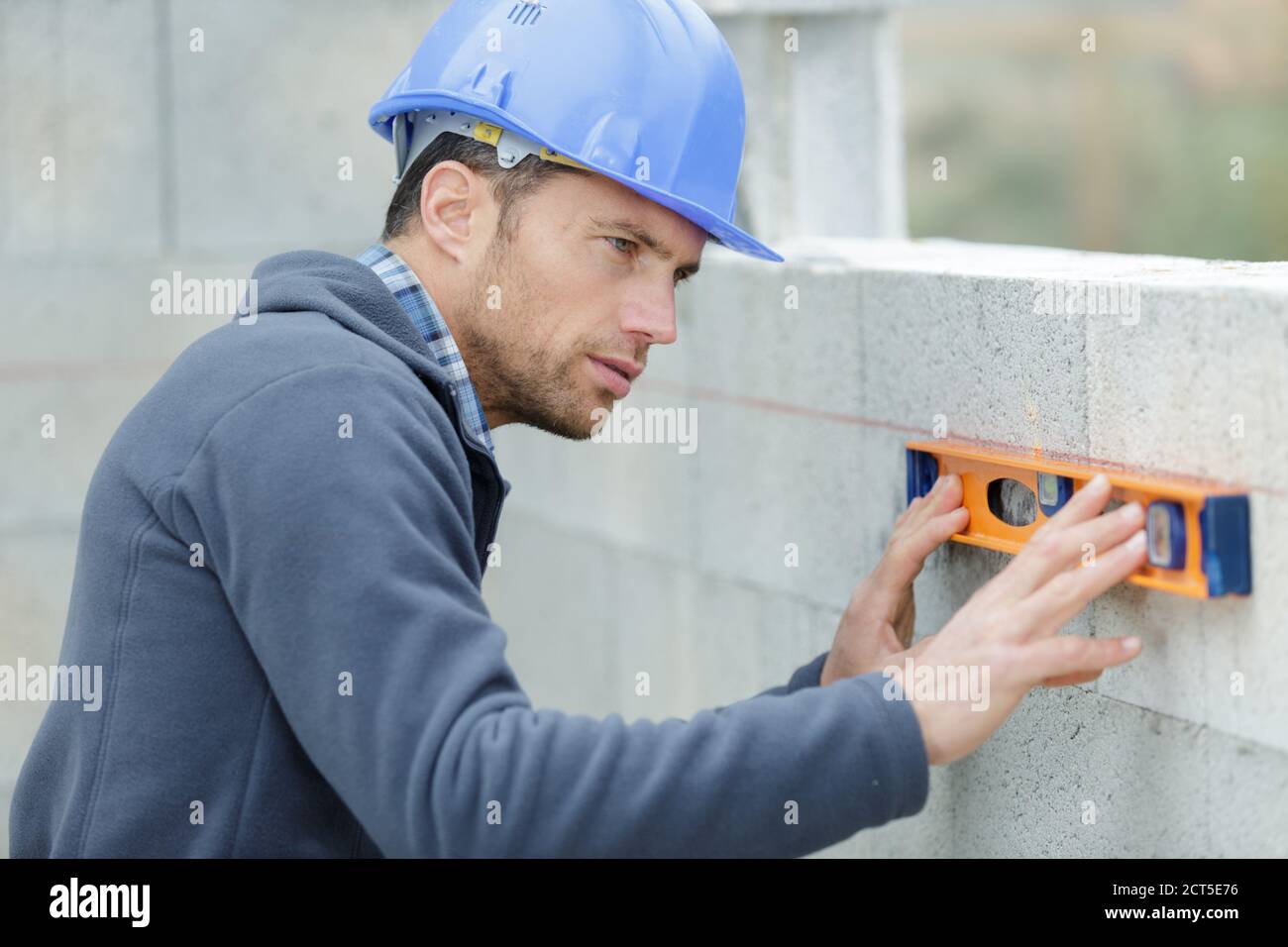 concentrated builder using a level on an exterior wall Stock Photo - Alamy