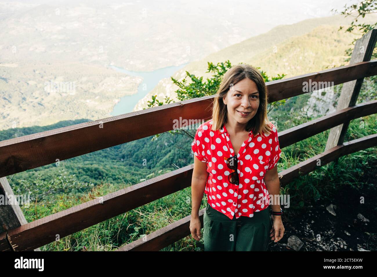 Young female nature explorer enjoying the view from mountain viewpoint ...