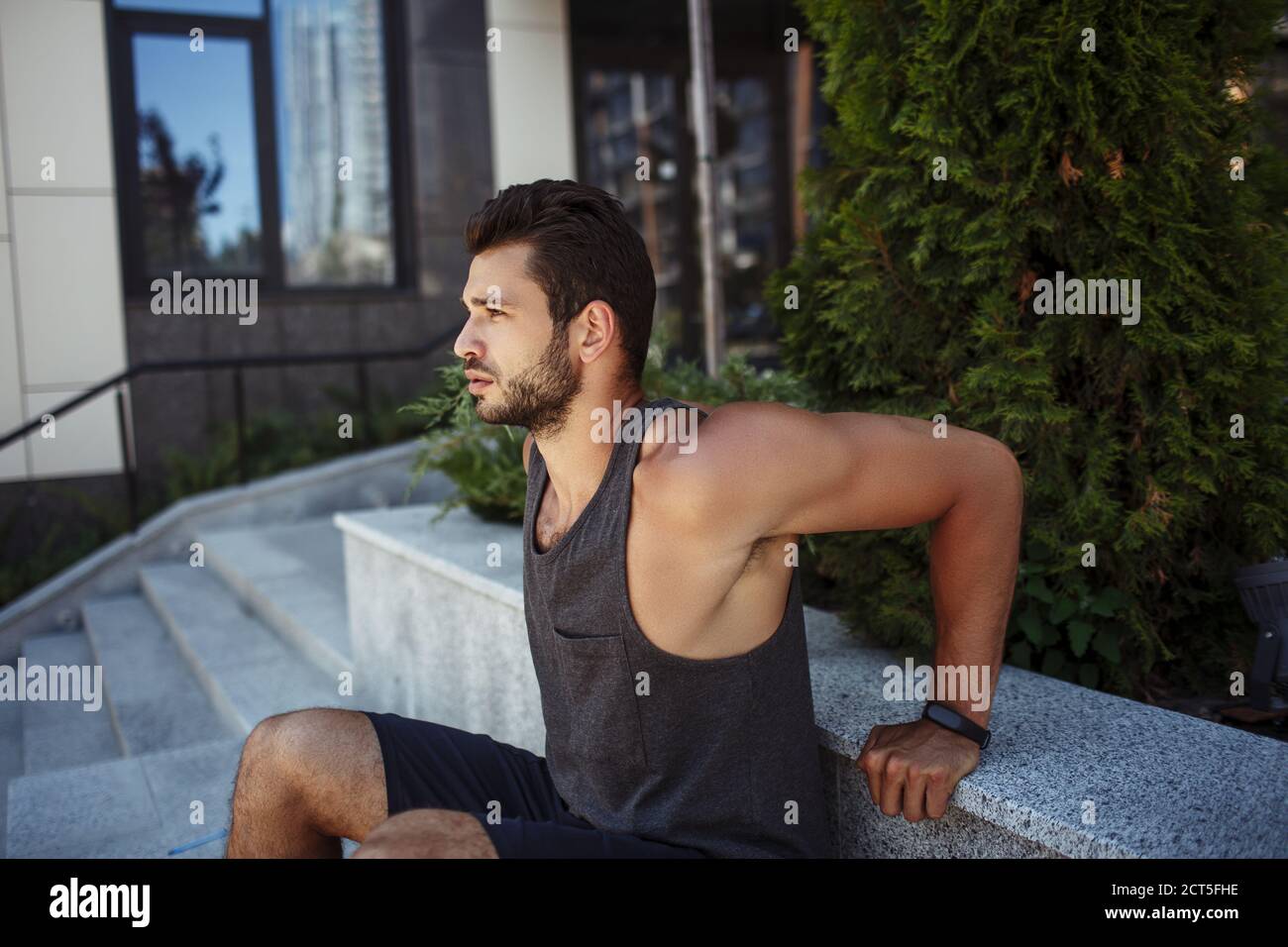 Young man exercising outside. Guy doing reverse push ups holding hands ...