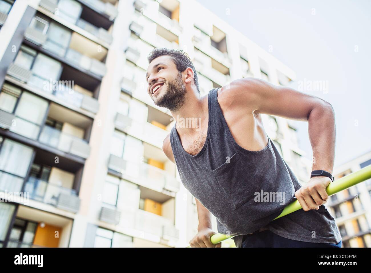 Young man exercising outside. Cheerful positive sportsman holding hands ...