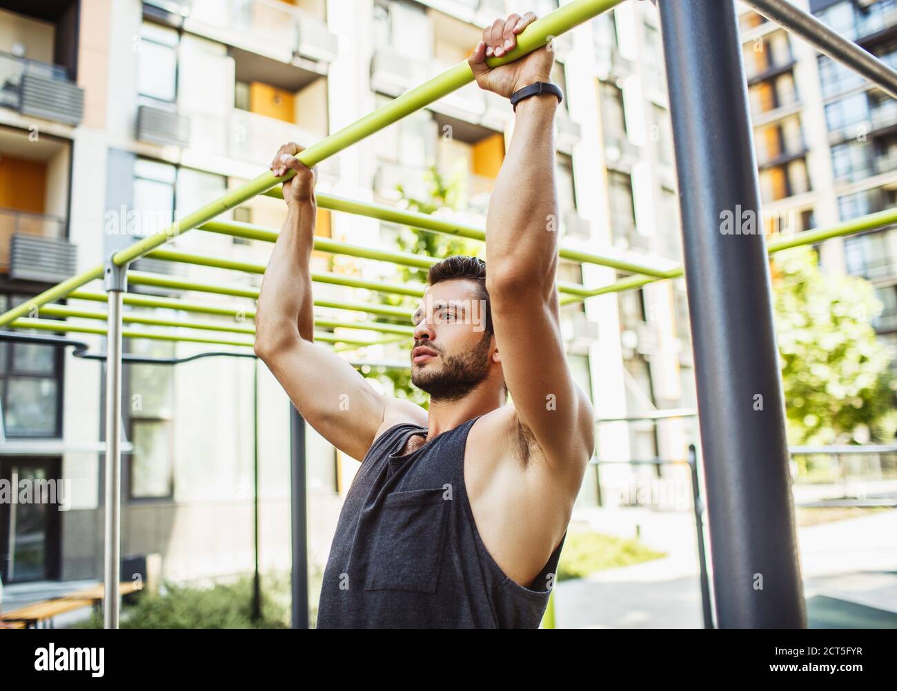 Young man exercising outside. Concentrated sportsman holding training ...