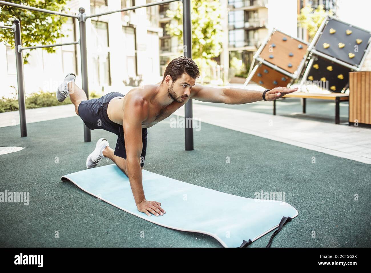 Young man exercising outside. Sportsman stand in one leg and hand plank ...