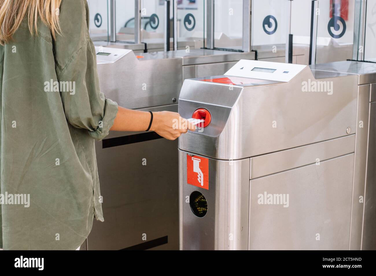 Unrecognizable female putting card into gate machine and buying ticket ...