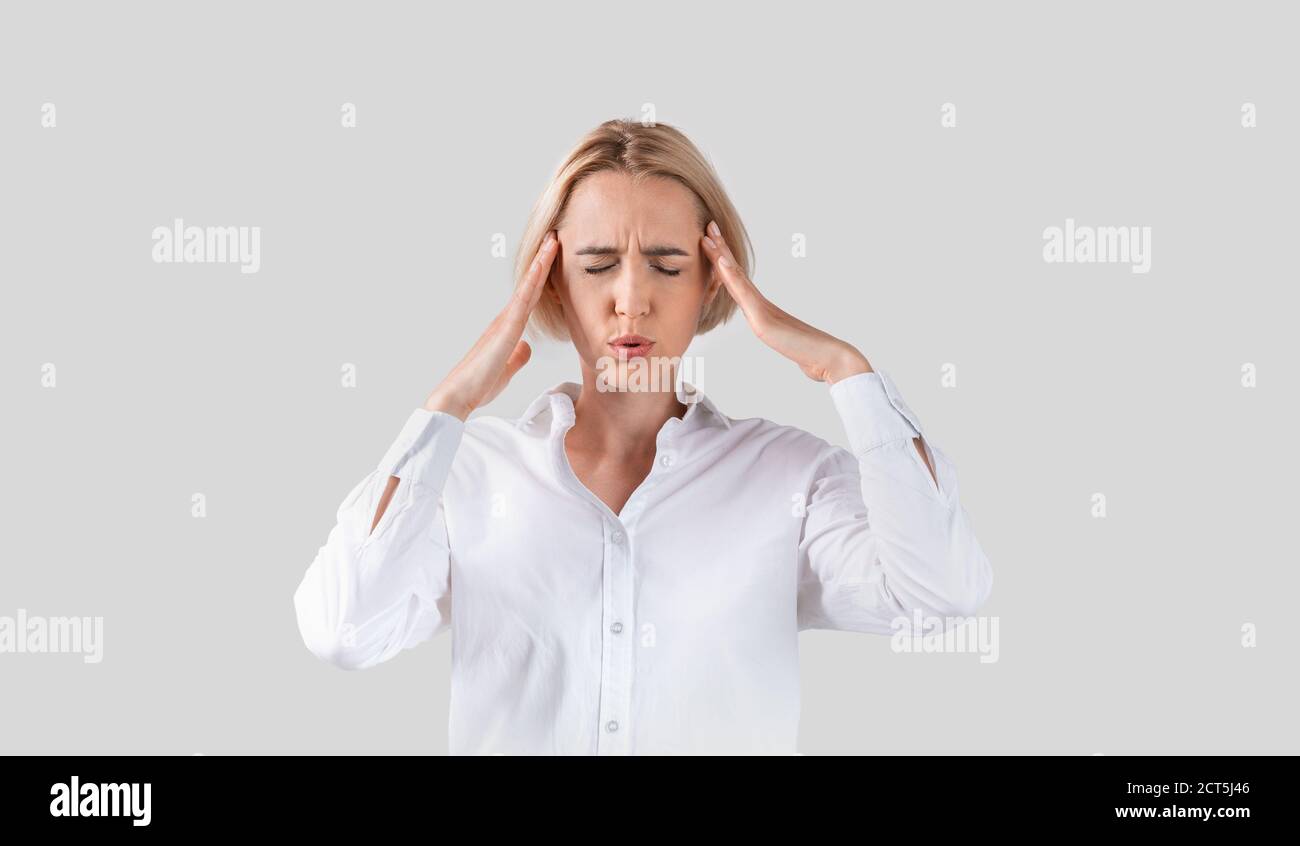 Overworked office employee suffering from severe headache on light grey ...