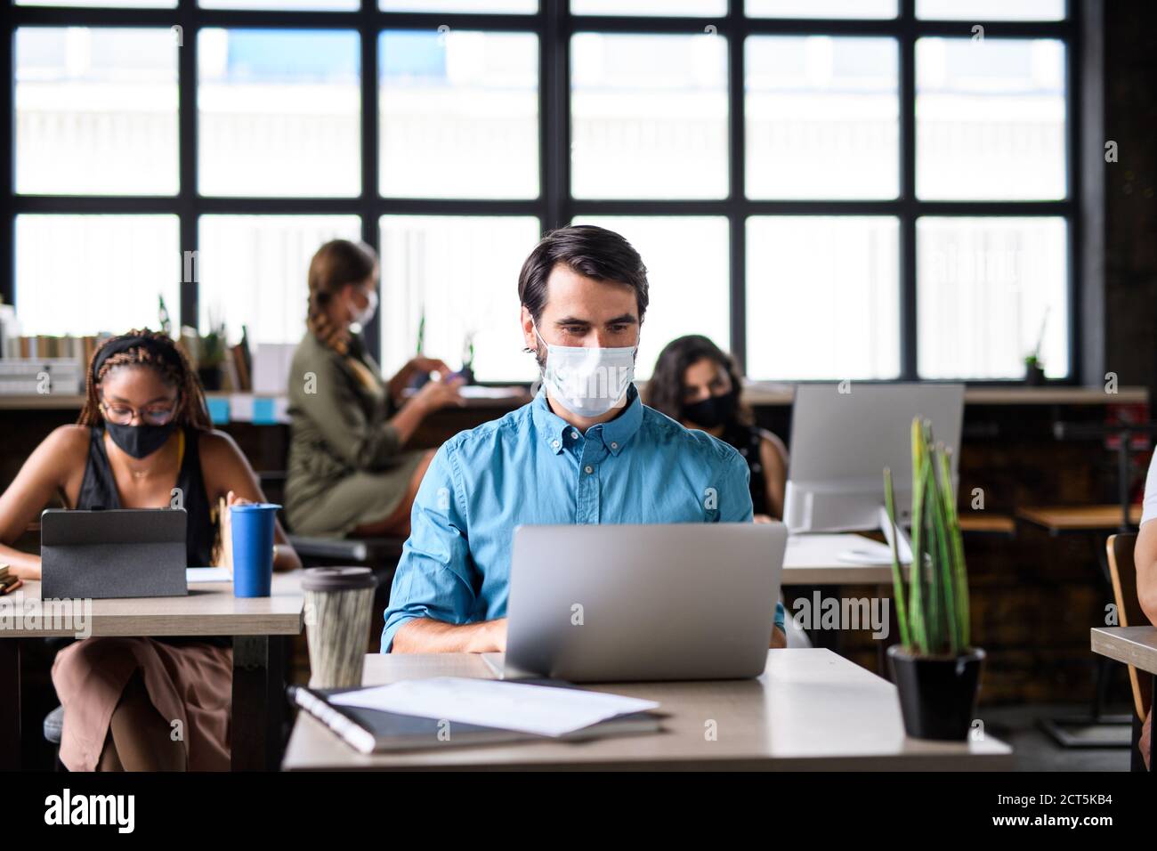 Business people with face masks indoors in office, back to work after ...
