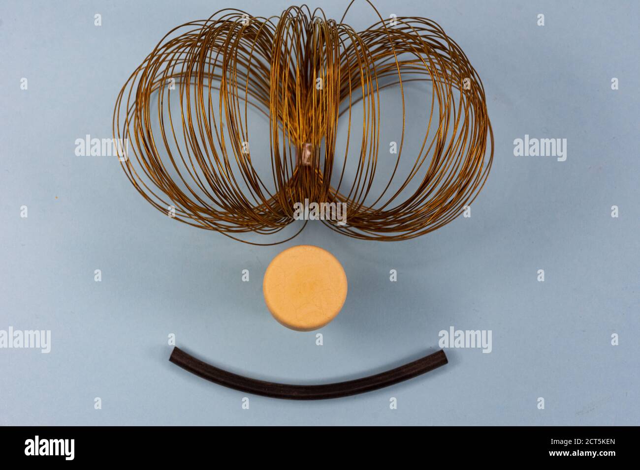 Tangle of thin brass wire and objects for simulating of a happy face ...