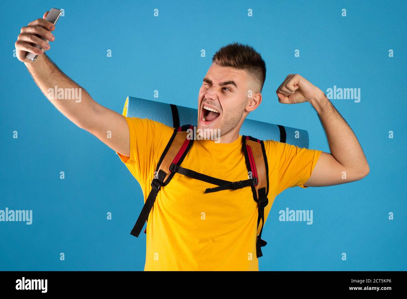Cool young guy with tourist equipment taking selfie on smartphone over ...