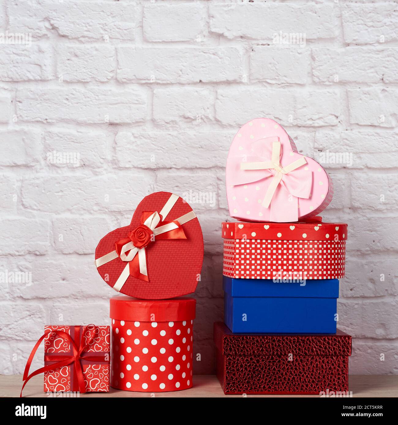 stack of various boxes with gifts on white brick background, festive ...