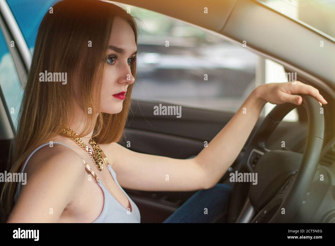 Young beautiful woman driving a new car. Focused blonde drives a car ...