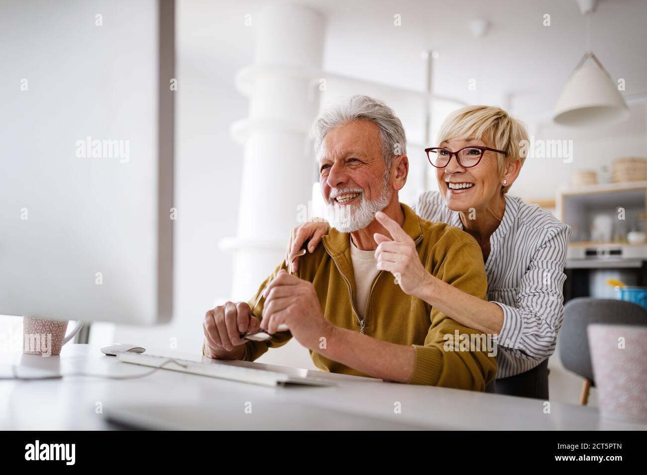 Senior woman helping senior man to use computer Stock Photo - Alamy