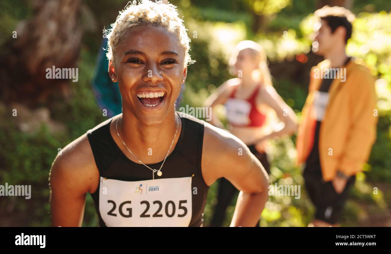 Cheerful cross country marathon runner standing outdoors looking at ...