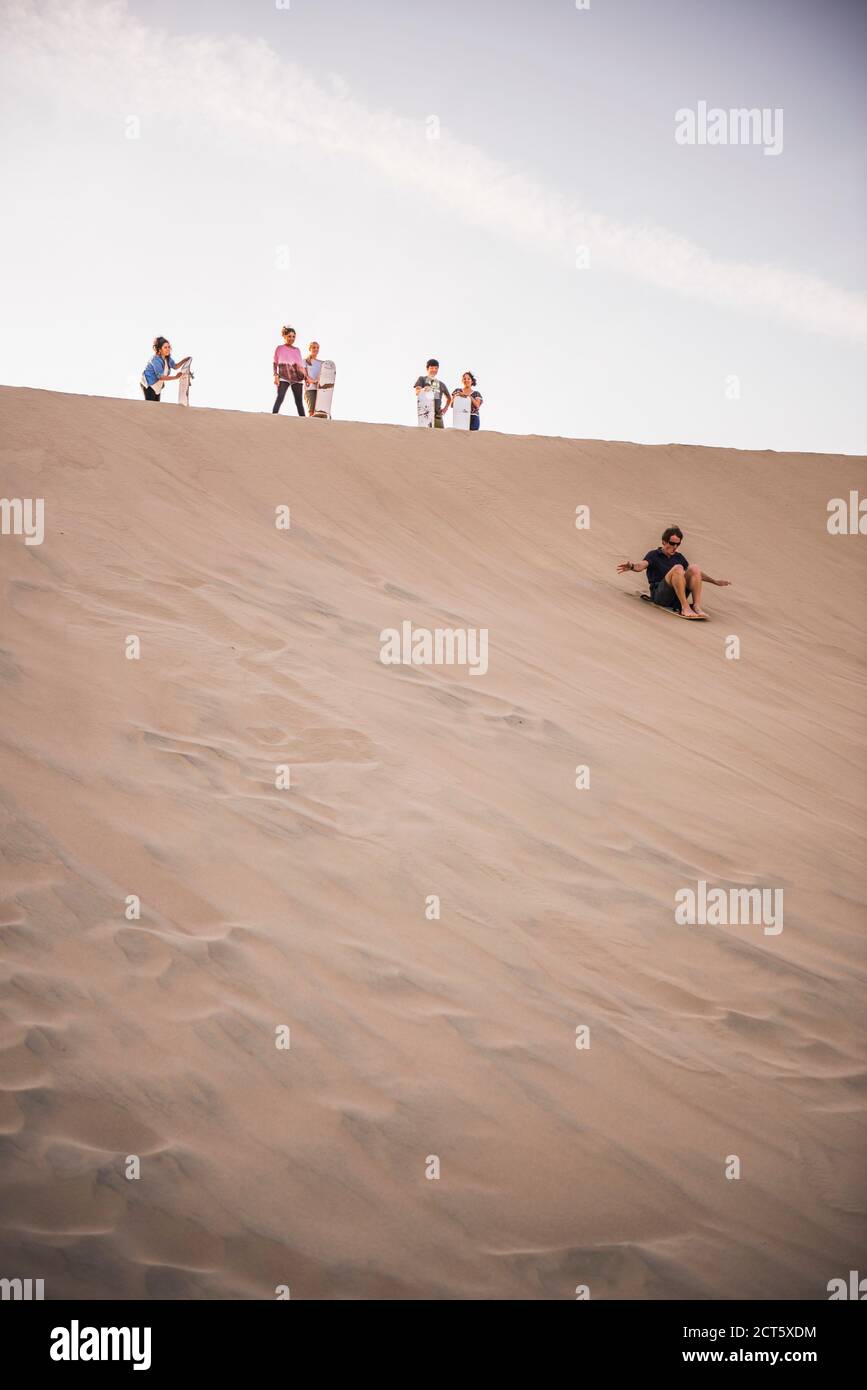 Sand boarding on dunes in the desert at Huacachina, Ica Region, Peru ...