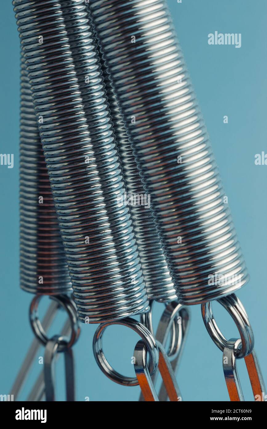 Pulling down twisted metal coil springs on blue background with ...