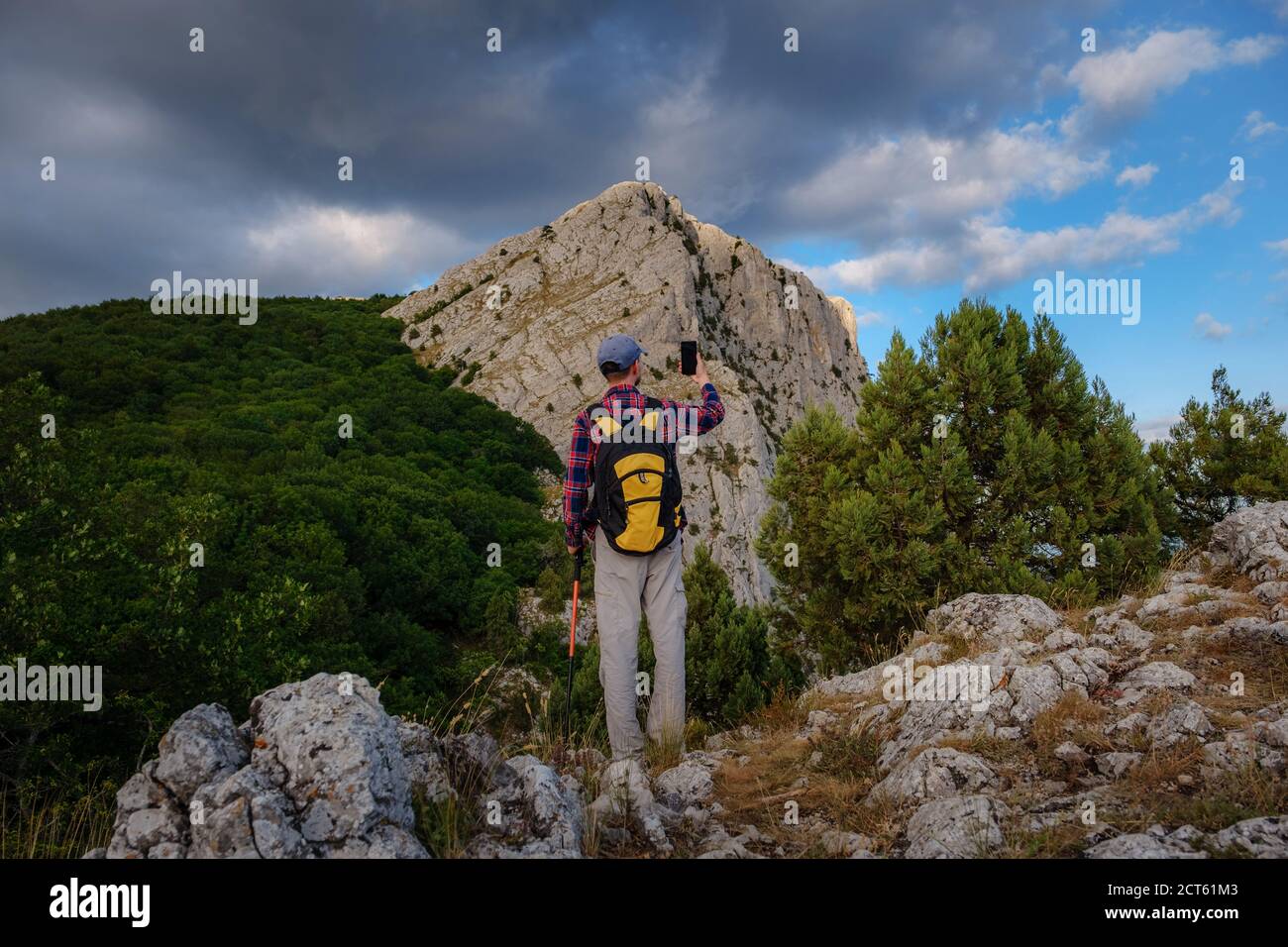 Strong man hiker taking photo with smart phone at mountain peak ...