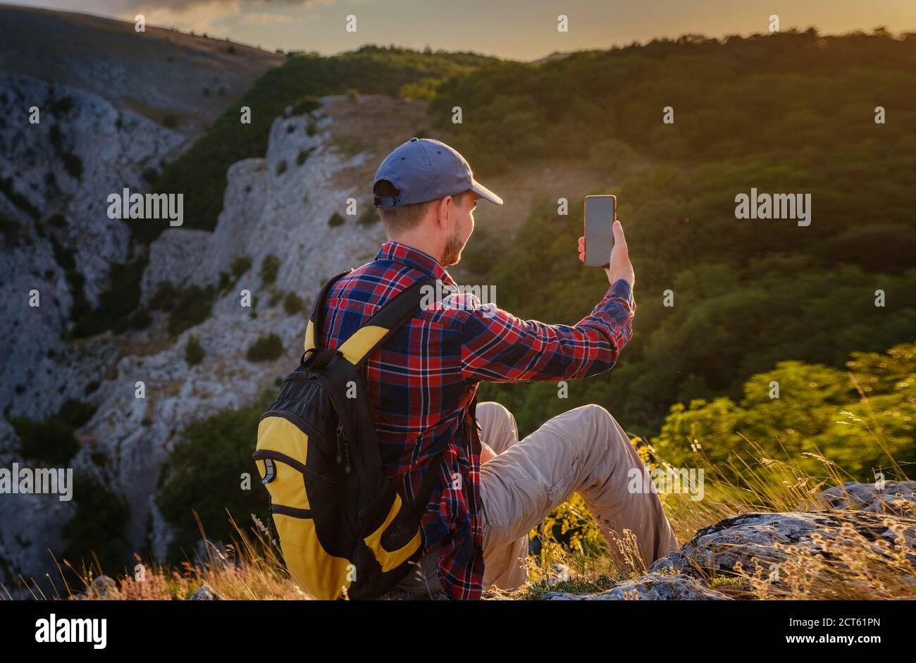 Strong man hiker taking photo with smart phone at mountain peak ...