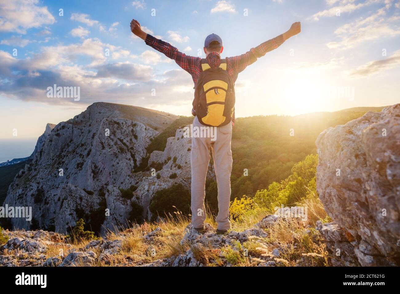 Adventurous man is on top of the mountain and with raised hands and ...